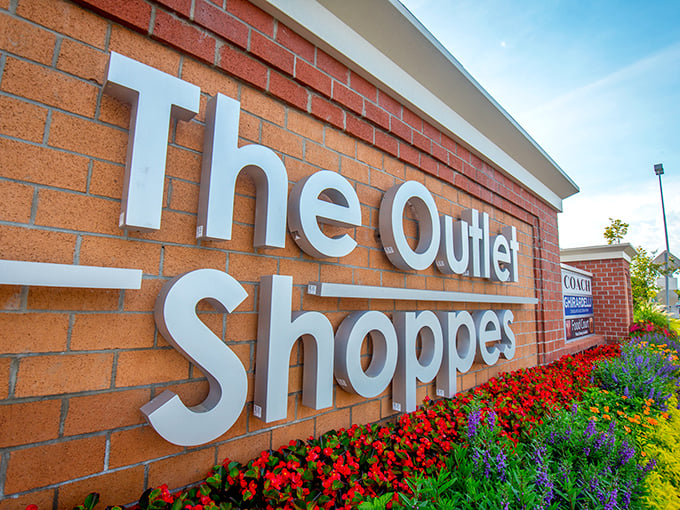 The entrance sign blooms with promise, much like your wallet will bloom with savings. Vibrant flowers frame the brick-mounted welcome to bargain paradise.