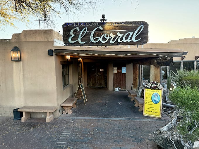 The weathered wooden sign welcoming you to El Corral promises authenticity before you even step inside. Desert landscaping frames this Tucson treasure like nature's own welcome mat.