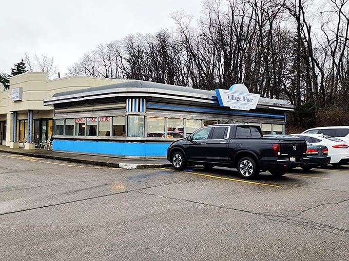The classic blue-and-white exterior of Village Diner stands like a time capsule of Americana, beckoning hungry travelers with promises of comfort food perfection.