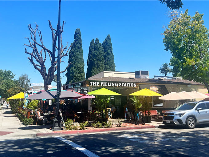 The Filling Station's sunny exterior with its vibrant yellow umbrellas isn't just inviting—it's practically waving you in for breakfast bliss.
