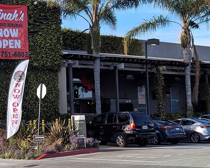 Palm trees frame Dinah's Comfort Kitchen like nature's welcome committee. The ivy-covered walls and "NOW OPEN" sign promise good things await inside.
