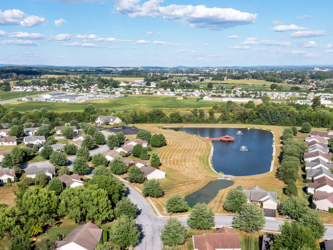 Aerial dreams come true! Arbor Gate's perfectly arranged homes surround a glistening pond, like a retirement community designed by someone who actually understands what "golden years" should mean.