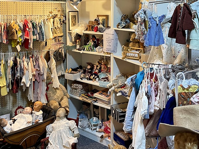 Vintage children's clothing and dolls await new homes. That porcelain face has seen more decades than most of us, yet hasn't aged a day.