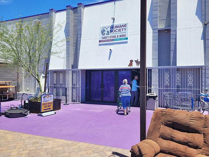 The purple doors of the Humane Society Thrift Store beckon like a portal to bargain paradise, complete with adorable dog silhouettes standing guard above.