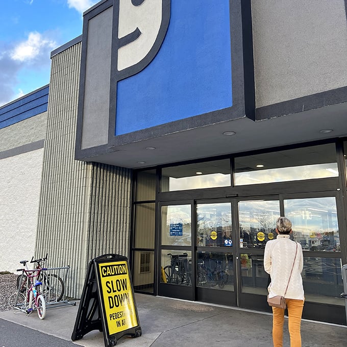A single customer pauses in front of the iconic smiling ‘g’ logo, ready to step into this thrift paradise where yesterday’s discards are given a second chance at greatness.