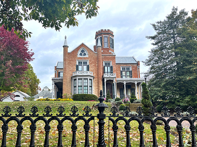 The red brick façade and distinctive tower of The Castle stand proudly behind wrought iron fencing, like a Victorian dream that somehow materialized in small-town Ohio.