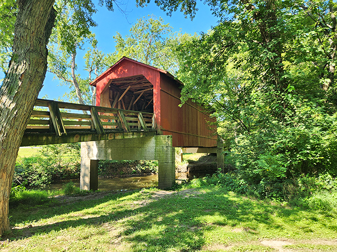 The classic red siding of Sugar Creek Covered Bridge pops against Illinois greenery like a Norman Rockwell painting come to life.