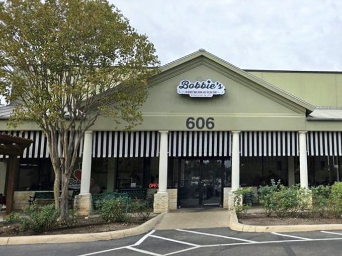 The pale green exterior with classic black and white awnings isn't trying to impress anyone—it's saving all that energy for what happens in the kitchen.