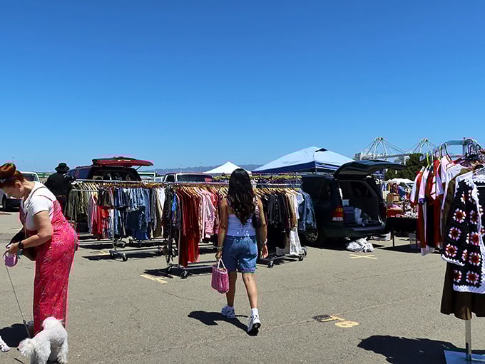 Vintage fashion hunters browse racks of clothing treasures under perfect California skies at Alameda Point's sprawling outdoor marketplace.