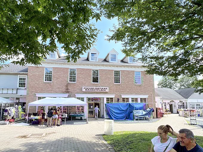 The colonial-style brick building houses treasure hunting adventures beneath its dormer windows, while outdoor vendors create a festive marketplace atmosphere under the summer sky.