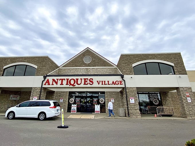 The stone facade of Antiques Village welcomes treasure hunters with its bold red signage—a portal to yesterday that promises discoveries around every corner.
