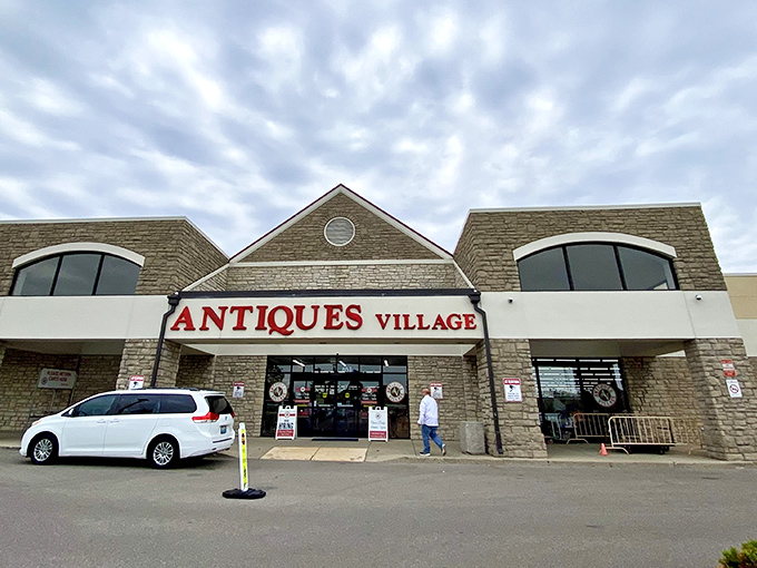 The stone facade of Antiques Village welcomes treasure hunters with its bold red signage—a portal to yesterday that promises discoveries around every corner.