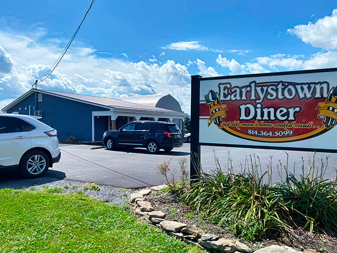 The humble facade of Earlystown Diner rises like a beacon for hungry travelers, with blue skies above hinting at comfort food and warm welcomes inside.