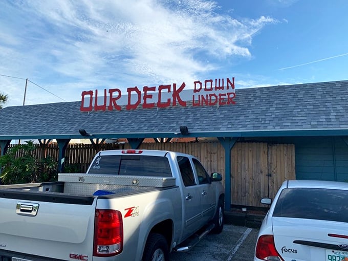 The bright red lettering against turquoise blue isn't just a sign—it's a promise of Florida seafood magic waiting beneath the Dunlawton Bridge.