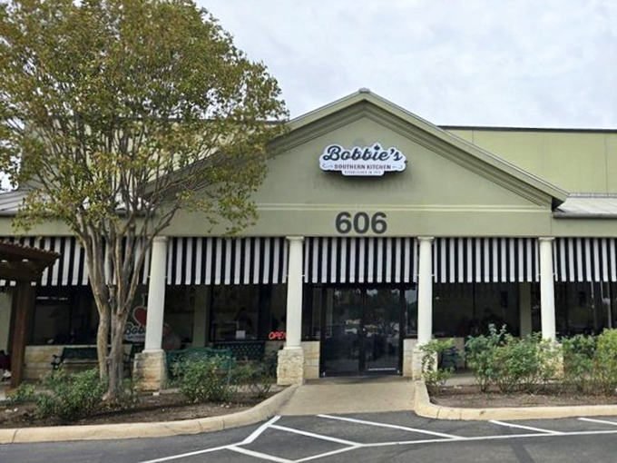 The pale green exterior with classic black and white awnings isn't trying to impress anyone—it's saving all that energy for what happens in the kitchen.