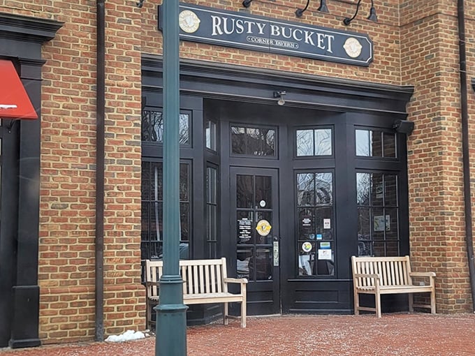 The brick façade and wooden benches at Rusty Bucket's entrance aren't just charming—they're practically whispering "come in, stay awhile" to every passerby.