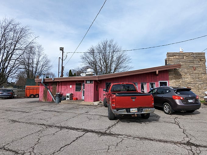 A wider view reveals the humble red building that houses burger greatness, where locals' vehicles gather like pilgrims at a flavor shrine.