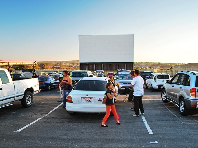 Cars line up at dusk facing the massive white screen, where cinematic magic awaits under the vast Mojave sky.