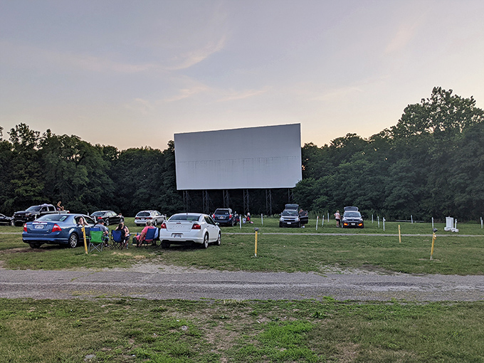 Cars lined up facing the massive white screen as dusk settles in—cinema's most perfect pairing since popcorn met butter.