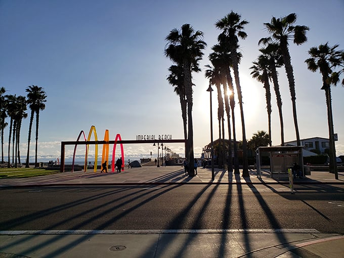 The setting sun casts long shadows across Imperial Beach, highlighting towering palms and the town’s relaxed charm along the Pacific shore.