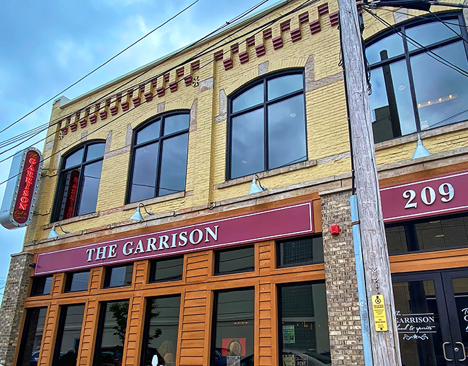 The golden-bricked façade of The Garrison stands like a culinary fortress on Fremont's Garrison Street, its burgundy awning beckoning hungry travelers inside.