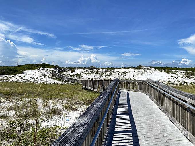 The wooden boardwalk winds through pristine white dunes, nature's perfect runway leading to paradise. No red carpet needed here.
