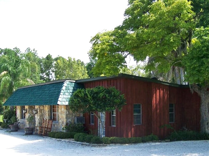 The rustic stone and wood exterior of Red Wing Restaurant stands like a culinary time capsule amid Groveland's lush Florida greenery.