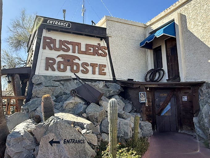The rugged stone entrance to Rustler's Rooste stands like a Western movie set come to life, complete with desert cacti and that iconic sign promising adventure.