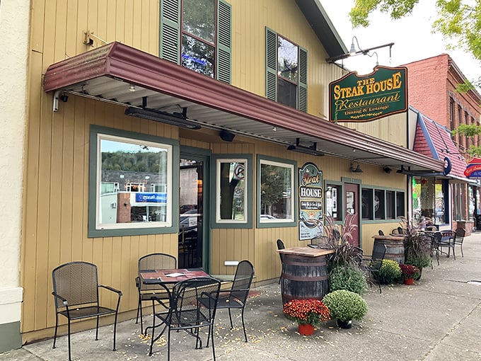 The charming exterior of The Steak House beckons hungry travelers with its classic awning and inviting outdoor seating—a Main Street fixture that promises culinary comfort.