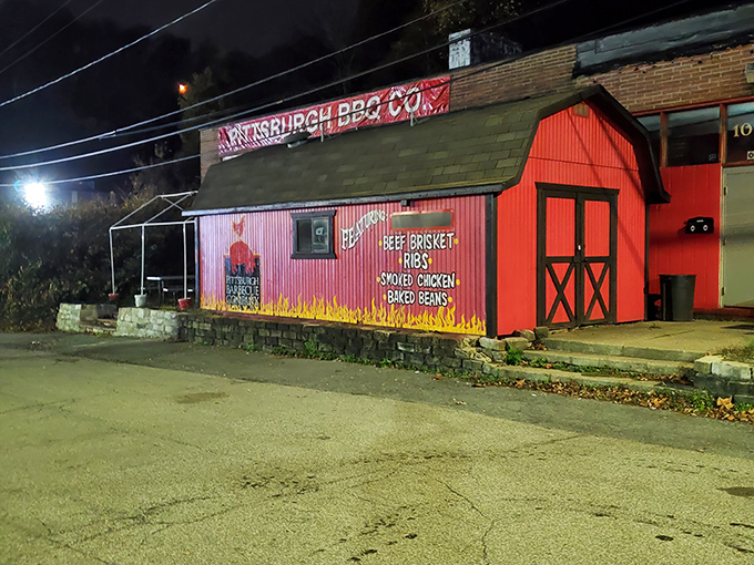 By night, the barn-shaped barbecue joint transforms into a glowing temple of smoked meats, its fiery painted exterior a perfect preview of the flavor explosions waiting inside.