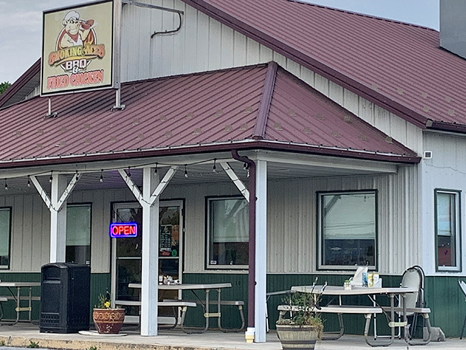 The humble white building with its burgundy roof might not look fancy, but that cartoon pig in sunglasses knows something you don't—barbecue paradise awaits inside.