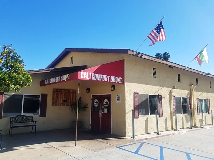 The humble stucco exterior of Cali BBQ might not scream "destination," but those flags flying proudly say "serious barbecue happens here."
