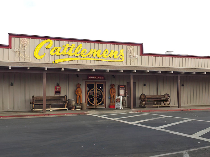 The iconic yellow Cattlemens sign beckons hungry travelers like a beacon of beef-related hope. Those wagon wheel doors promise Western hospitality and serious steak business inside.
