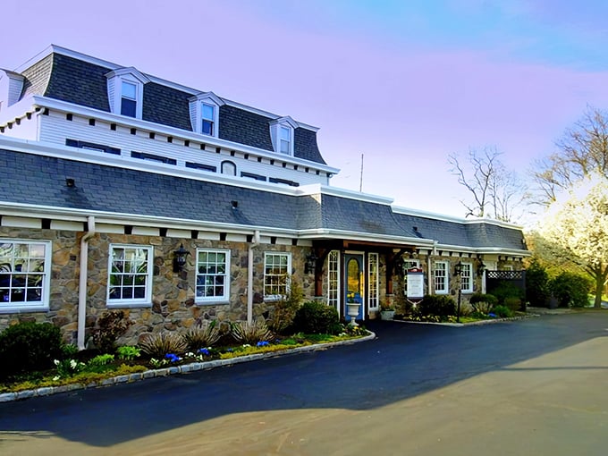 The historic stone façade of Spring House Tavern glows at dusk, its distinctive mansard roof and warm lighting promising culinary comfort within.