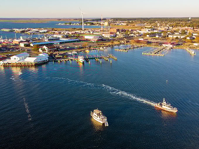 Crisfield's harbor at golden hour reveals its true identity—a working waterfront where fishing boats return with the day's bounty while modern wind turbines stand sentinel in the distance.