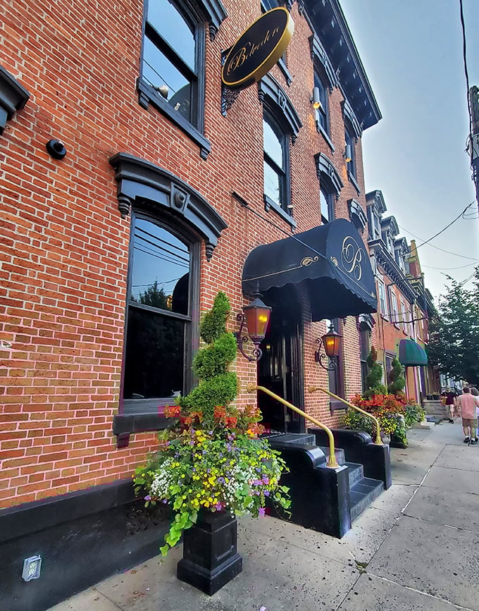 The historic brick façade of The Belvedere Inn welcomes visitors with elegant black awnings and vibrant flower boxes, a Victorian beauty in Lancaster's urban landscape.