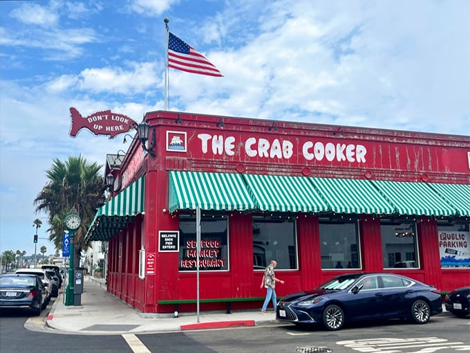 The iconic bright red exterior of The Crab Cooker stands out like a cheerful rebellion against Newport Beach's upscale aesthetic, complete with its famous fish-shaped "DON'T LOOK UP HERE" sign.