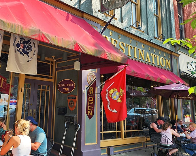 The red awning serves as a culinary lighthouse on Wellsboro's Main Street. Military flags proudly flutter above outdoor tables where diners savor meals and small-town ambiance.