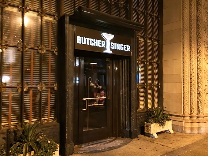 The unassuming entrance to Butcher and Singer beckons like a secret passage to the Rat Pack era, promising culinary time travel behind those elegant doors.