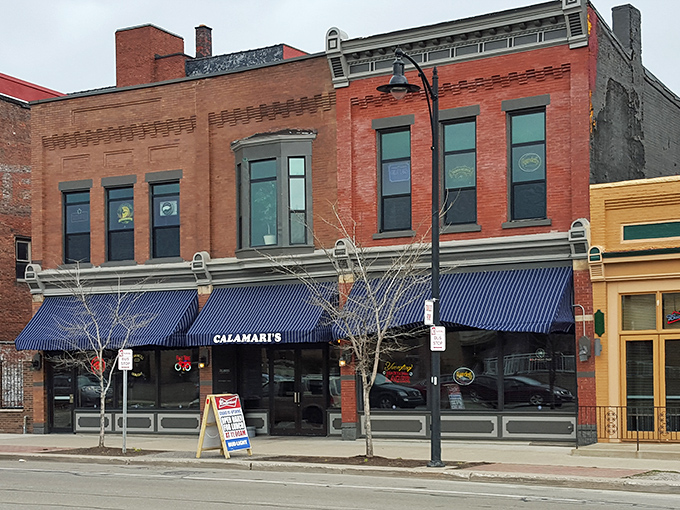 The historic brick façade of Calamari's Squid Row stands proudly on Erie's streetscape, its blue awnings beckoning hungry travelers like maritime flags.