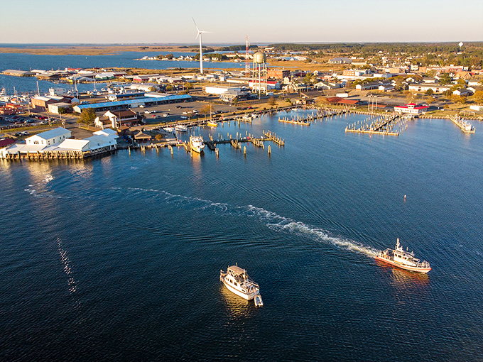 Crisfield's harbor at golden hour reveals its true identity—a working waterfront where fishing boats return with the day's bounty while modern wind turbines stand sentinel in the distance.