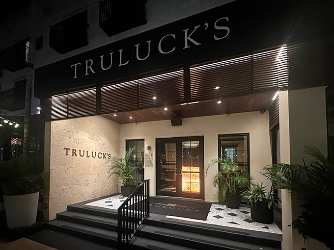 The elegant entrance to Truluck's glows like a culinary lighthouse, beckoning hungry travelers with promises of seafood treasures and perfectly seared steaks within.