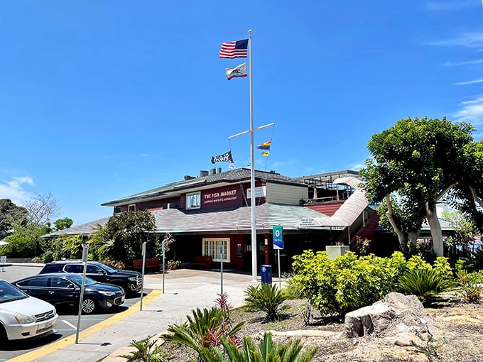 The Fish Market stands proudly against San Diego's blue sky, flags fluttering in the ocean breeze – a maritime beacon for seafood lovers seeking authentic coastal flavors.