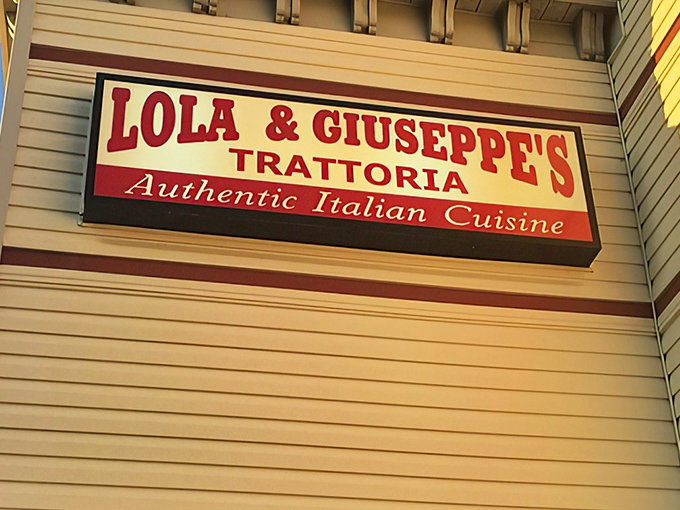 The unassuming exterior of Lola & Giuseppe's Trattoria, where green awnings and a simple sign hide culinary treasures that would make any Italian grandmother proud.