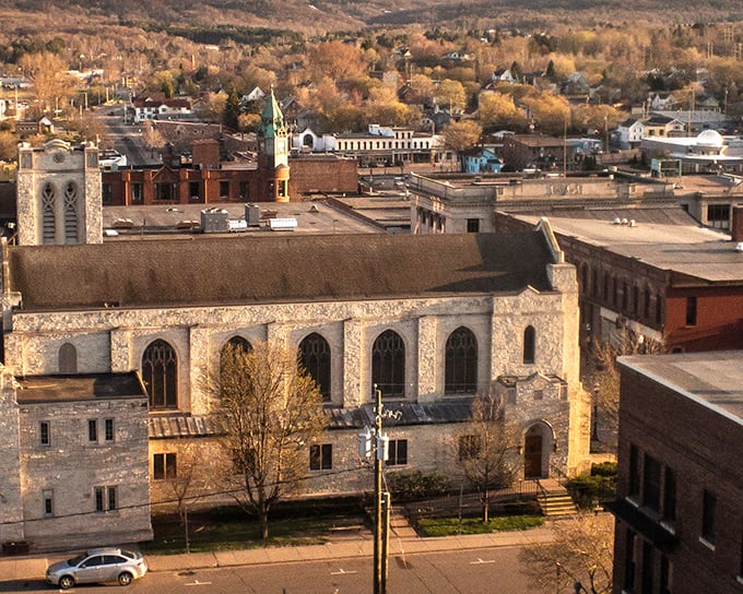 Downtown Marquette stretches invitingly toward the hills beyond, its flower-adorned lampposts and historic buildings creating a postcard-perfect main street scene.