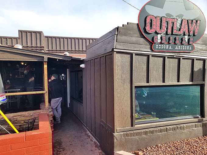 The iconic Outlaw Grill sign stands proudly against Sedona's majestic red rock backdrop, like a delicious mirage for hungry travelers.