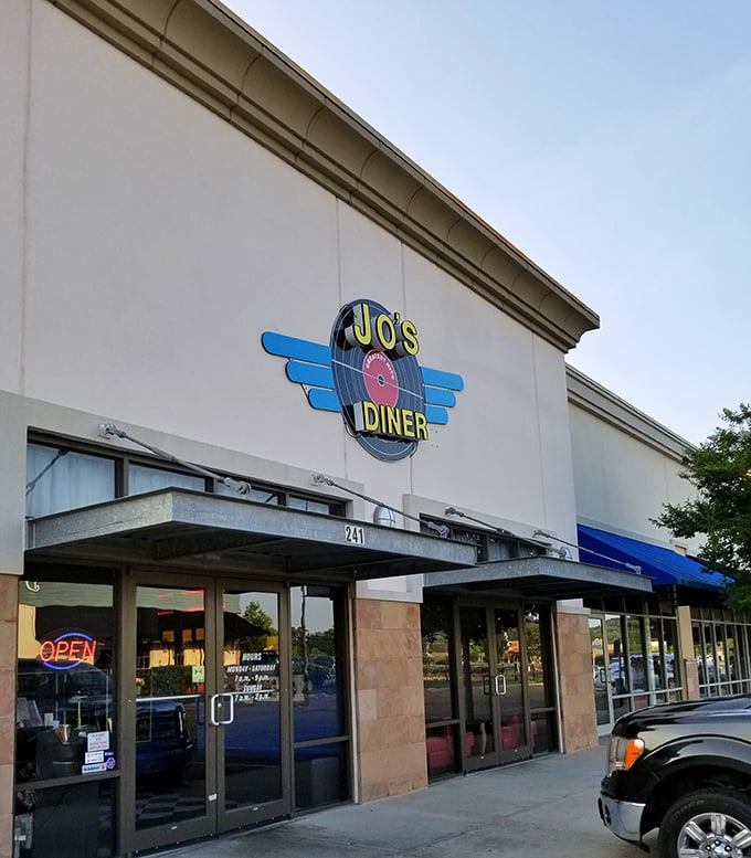 Jo's Diner's retro-styled exterior beckons with its vintage record logo and welcoming neon "OPEN" sign—like a time portal to simpler, more delicious days.