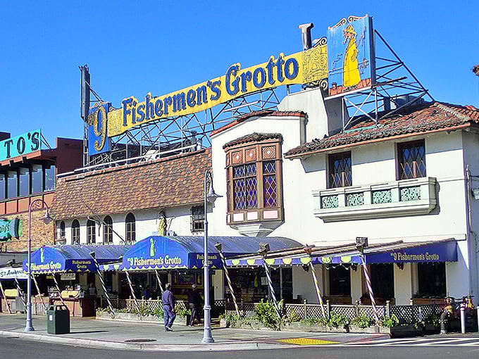 The iconic blue-and-gold sign of Old Fisherman's Grotto stands like a maritime beacon, promising seafood treasures within those Spanish-style walls.