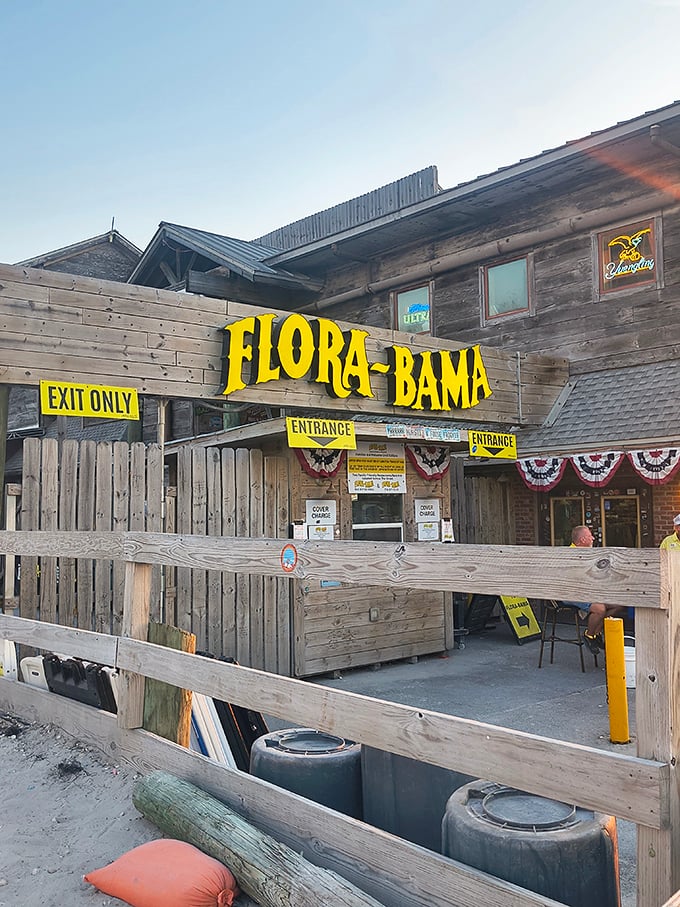 The weathered wooden exterior of Flora-Bama stands proudly on the state line, its bright yellow signage a beacon for hungry travelers seeking coastal treasures.