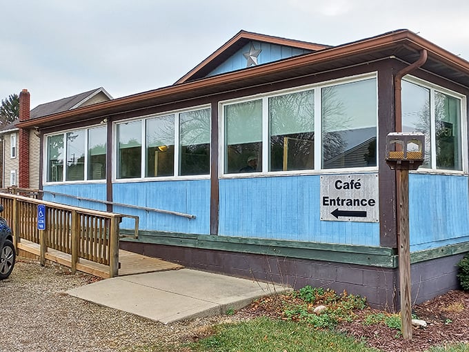 That "Café Entrance" sign might as well say "Portal to Comfort Food Heaven." The blue siding and sunlit windows promise zero pretension and maximum satisfaction.